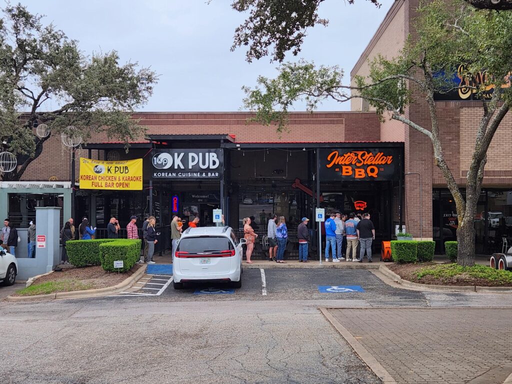 A group of people standing outside of a restaurant. - Treys Chow Down